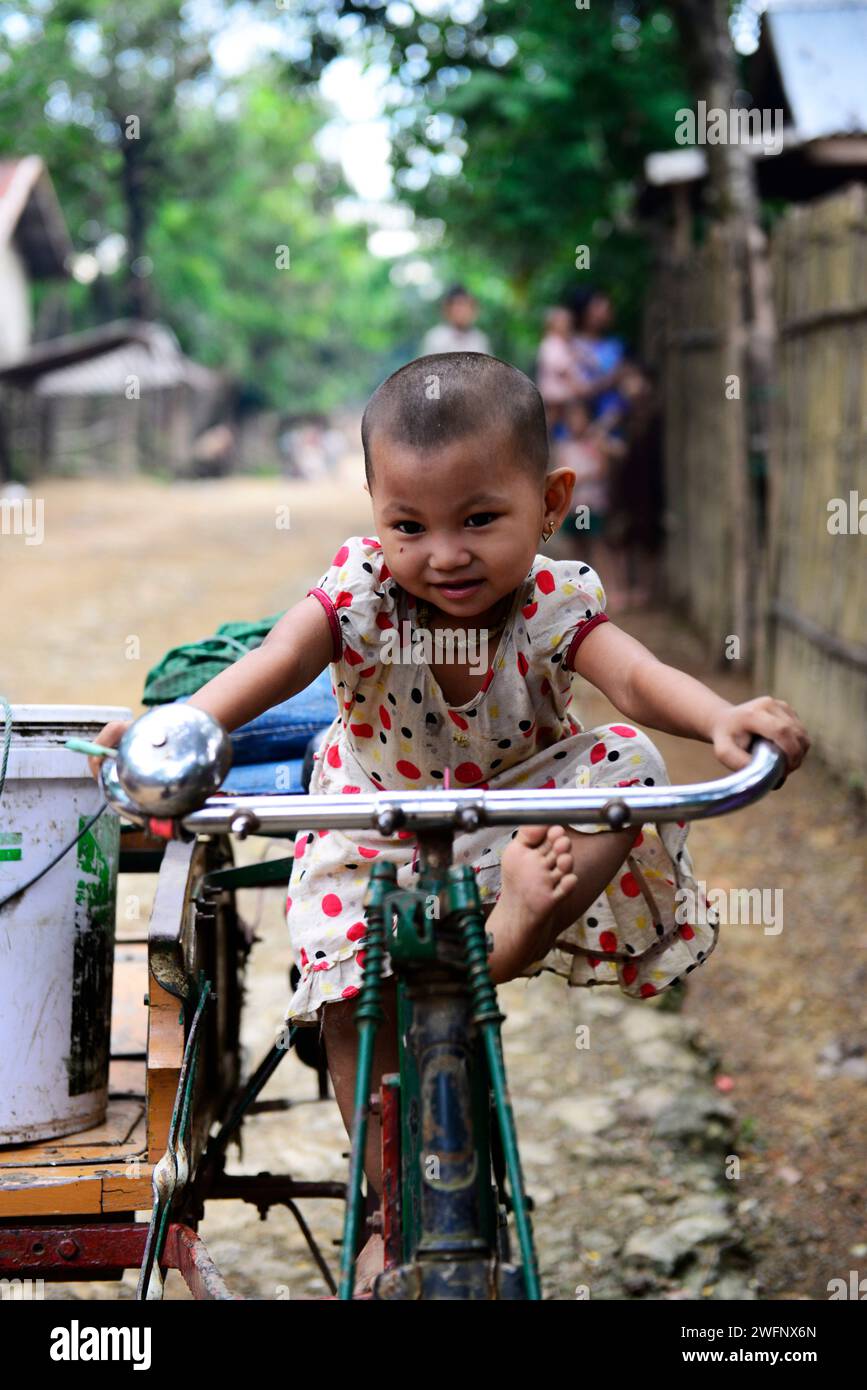 A cute Arakanese girl sitting on a bicycle in Mrauk-U, Rakhine State ...