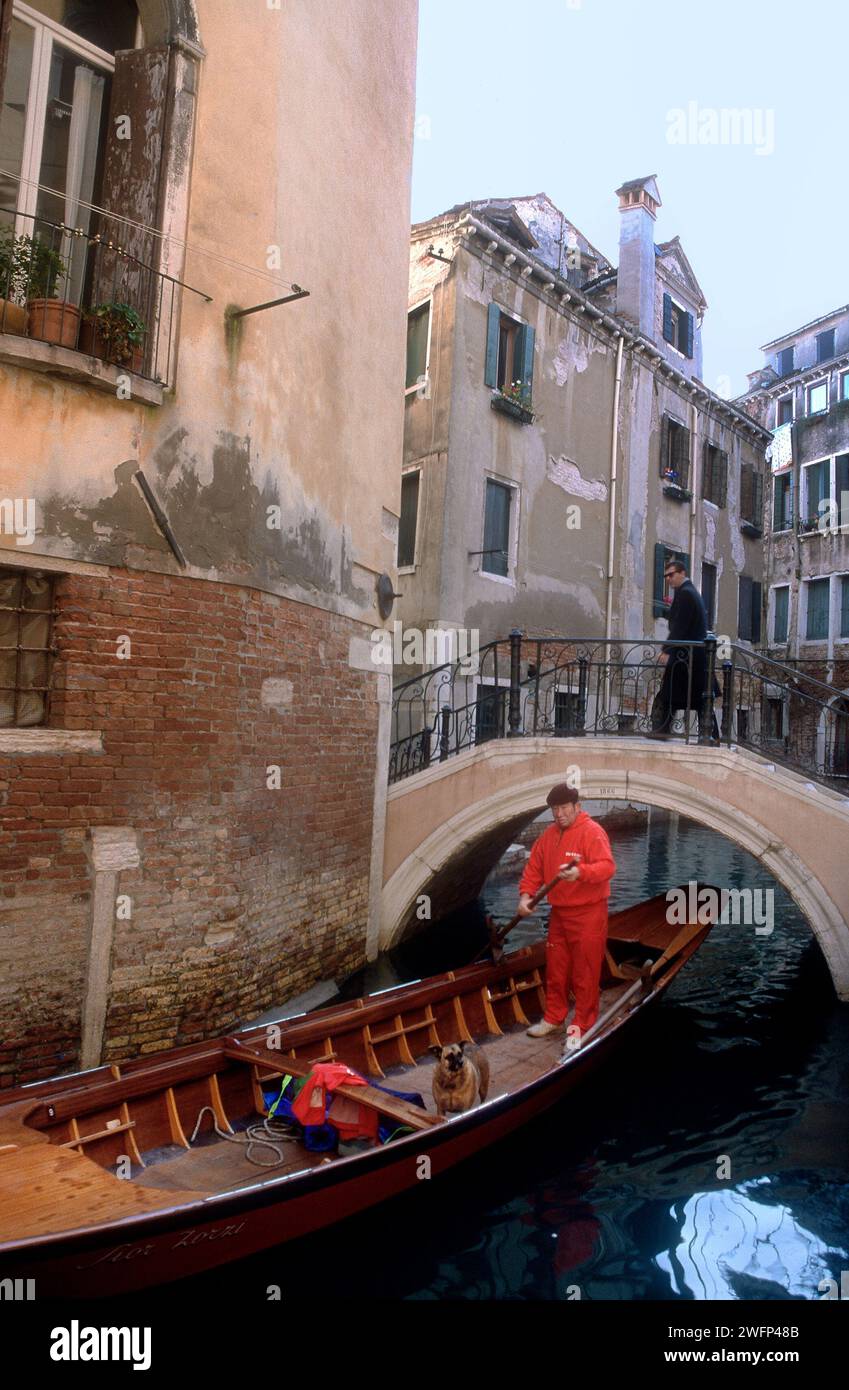 Man piloting boat on water canal in residential area, Venice, Italy ...