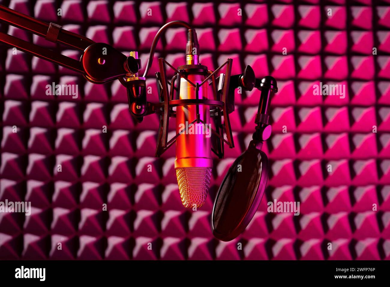 Professional studio microphone against acoustic foam panel background ...
