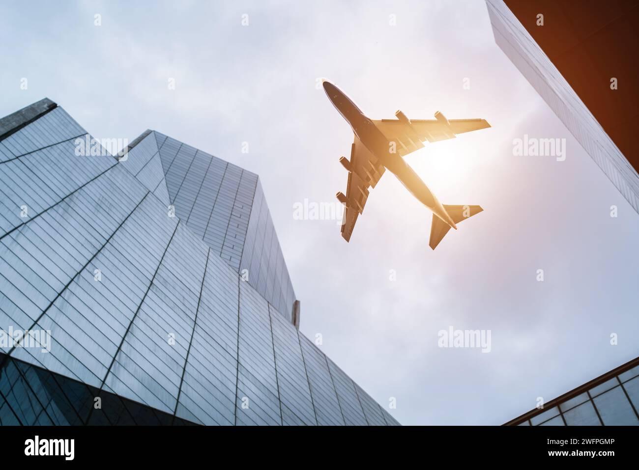 A commercial airplane soaring above modern buildings Stock Photo - Alamy