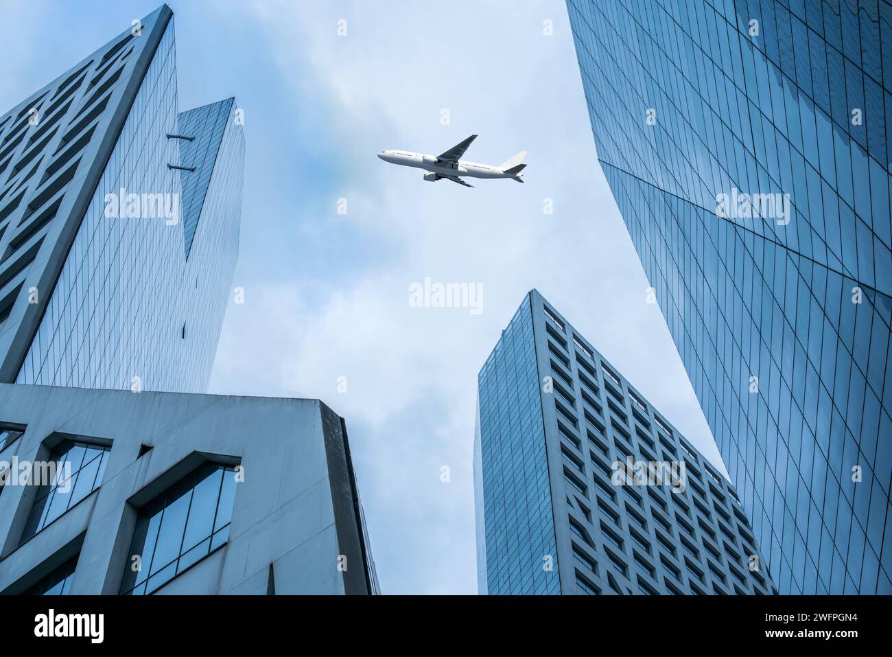 A commercial airplane soaring above modern buildings Stock Photo - Alamy