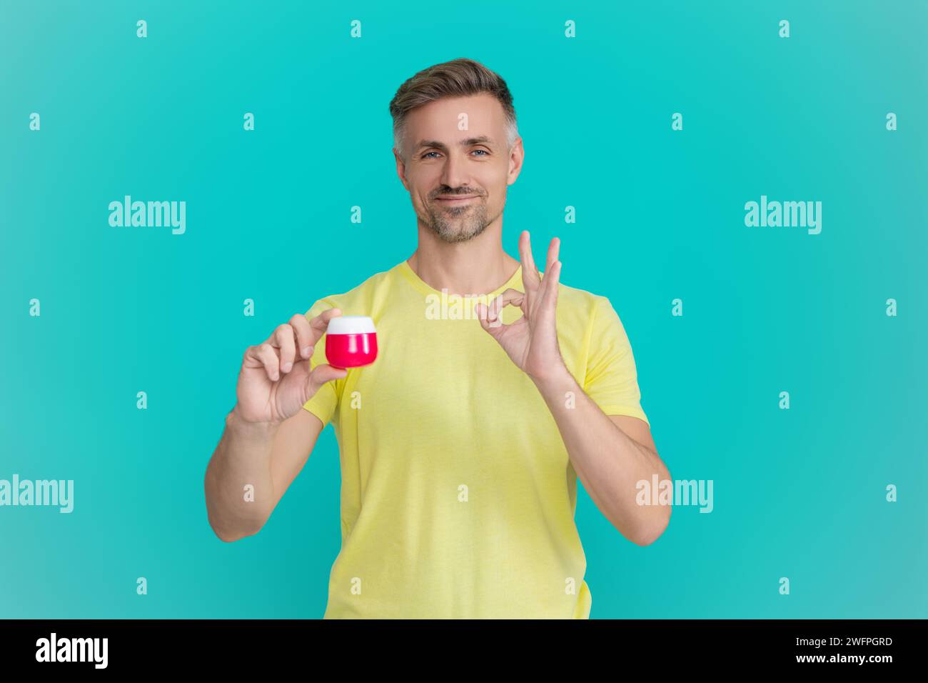 Man presenting male cosmetic product. Man showing face cream isolated ...