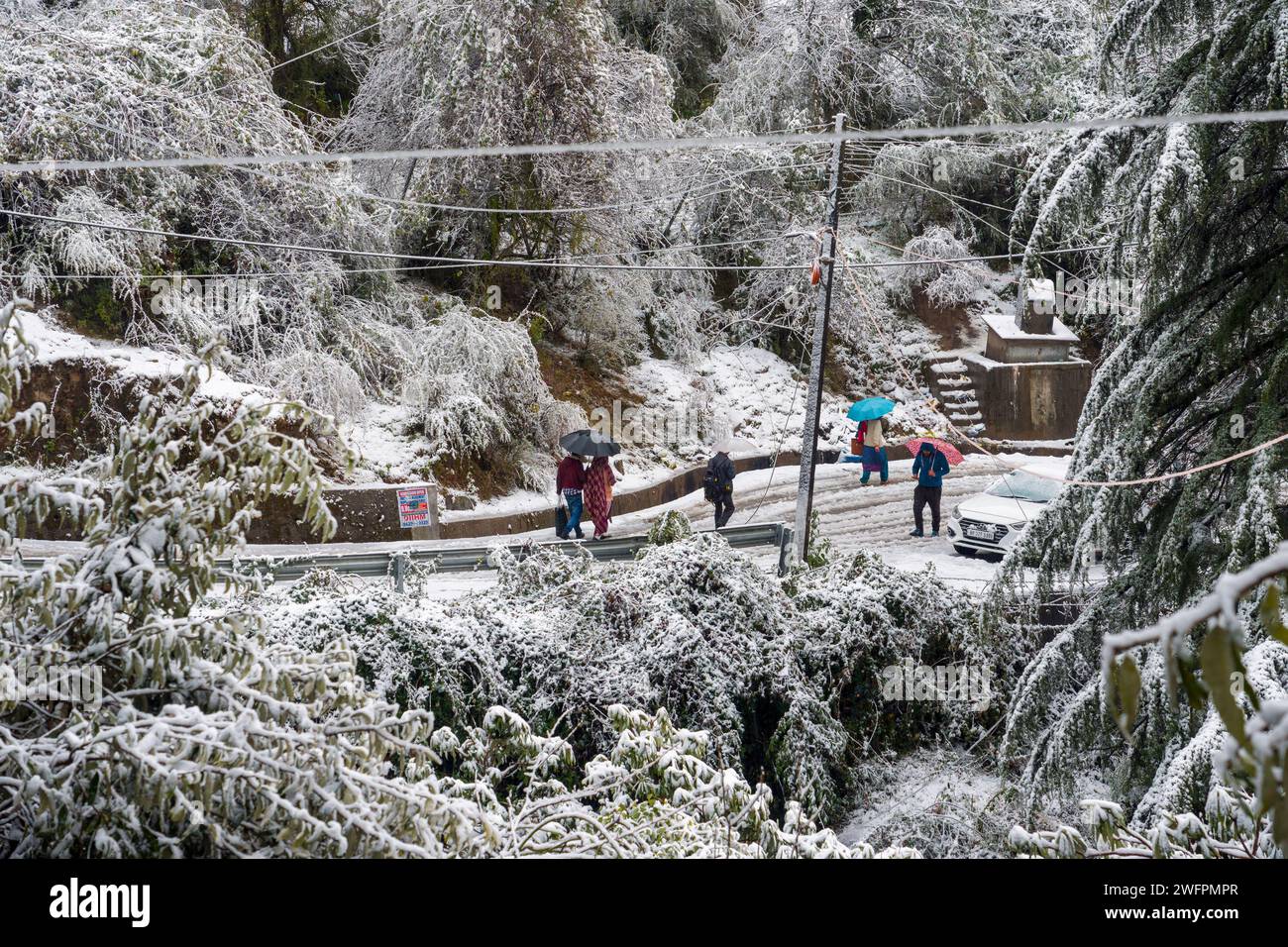 People walk under the rain on a road covered in fresh snow in ...