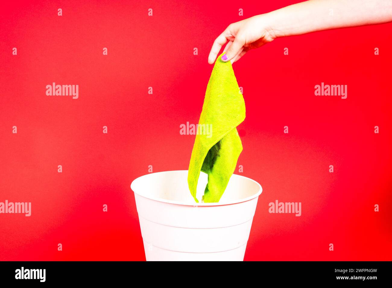 Throw napkin in trash bin, house cleaning rag in hand in front of trash ...