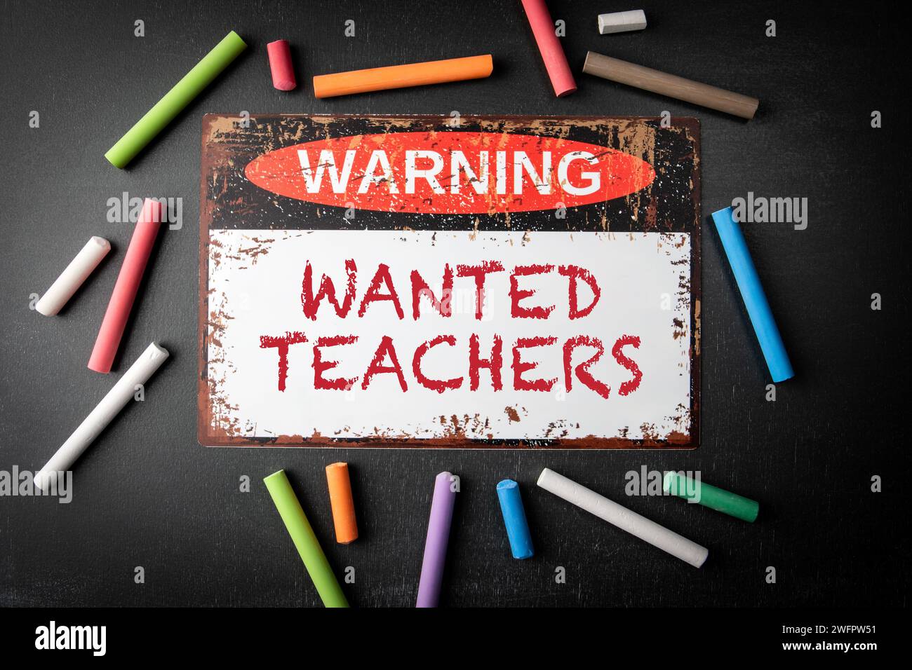 WANTED TEACHERS. Metal warning sign and colored pieces of chalk on a ...
