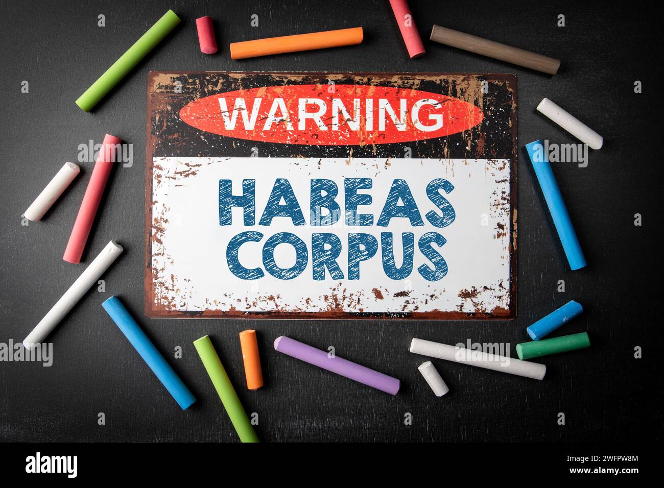 Habeas corpus. Metal warning sign and colored pieces of chalk on a dark ...