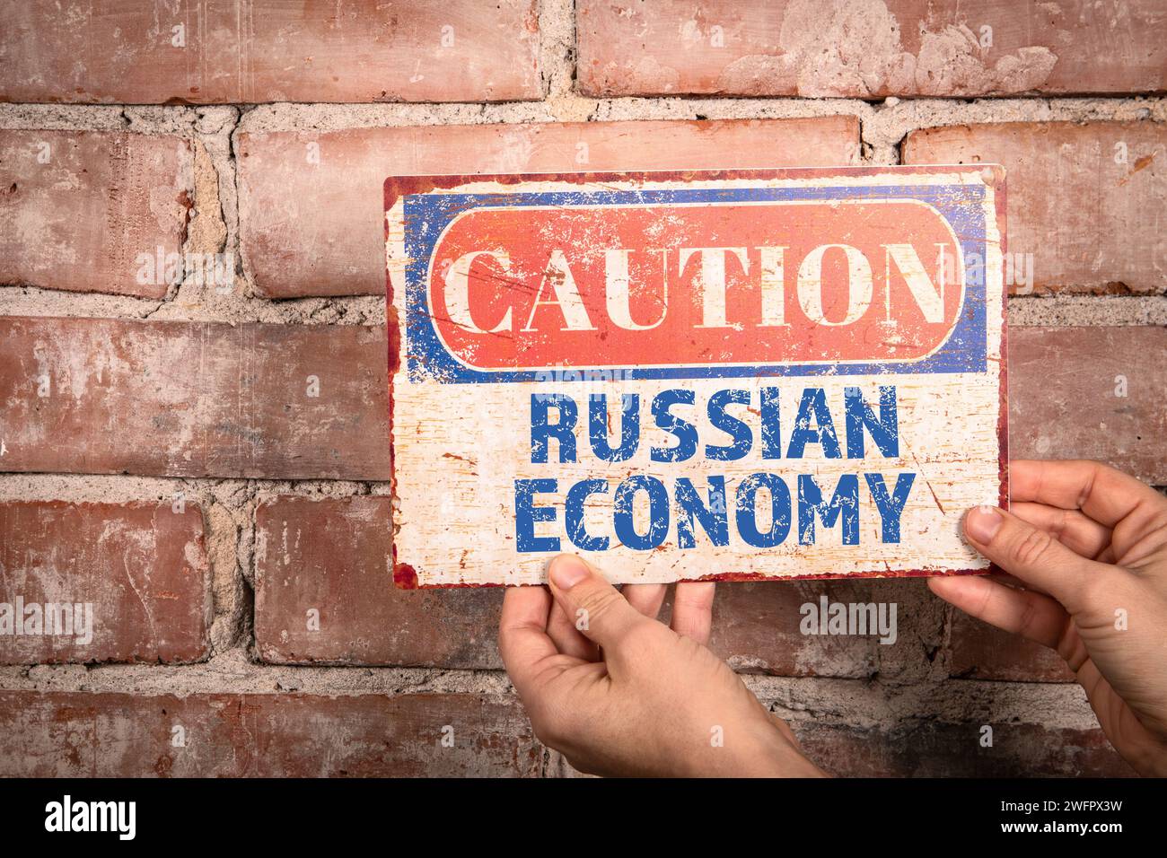 Russian Economy. Caution sign in a woman's hand on a brick background ...