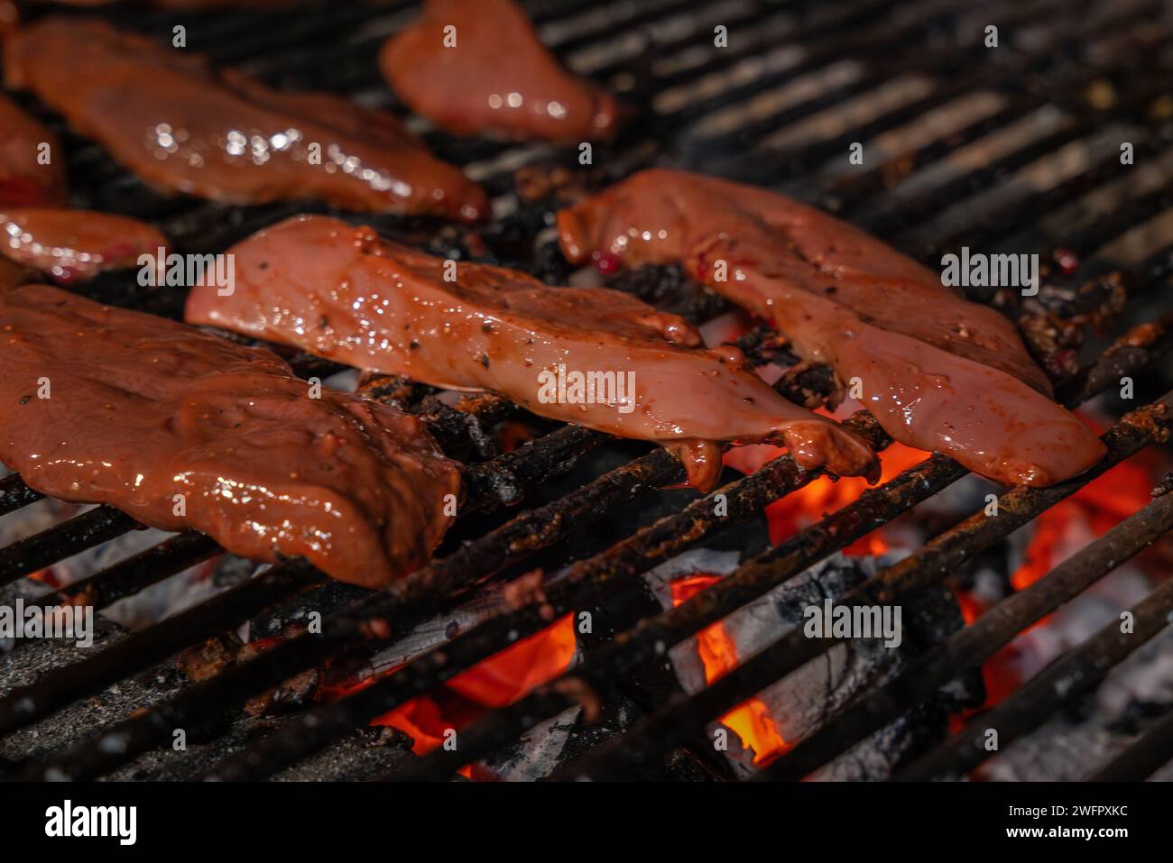 Lamb liver on the grill. A close-up of burning barbecue coals and lamb ...