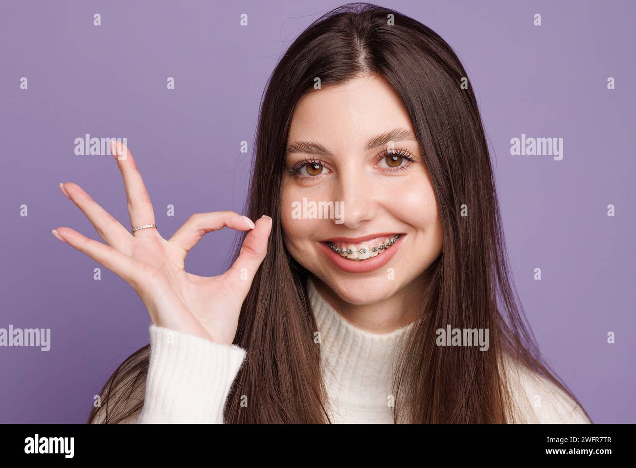 portrait of a girl with braces, woman happy with braces shows ok sign ...