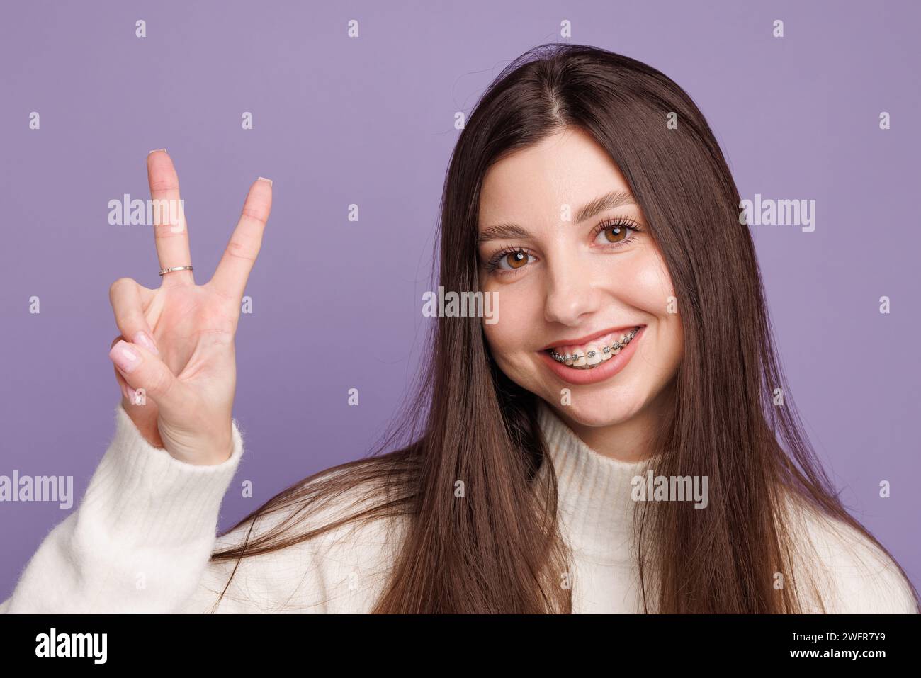 portrait of a girl with braces, woman happy with braces shows ok sign ...