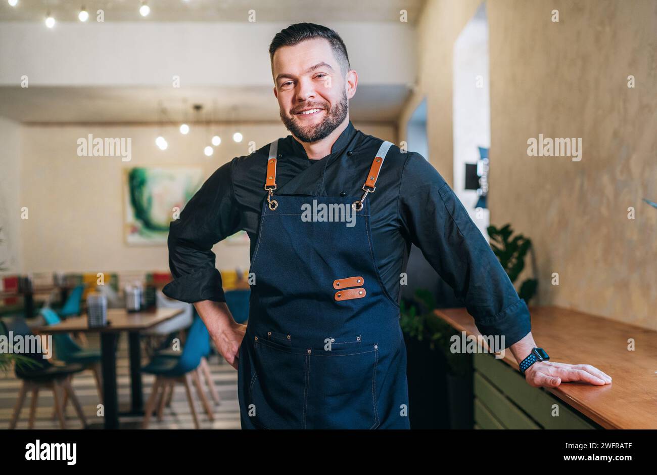 Portrait of happy smiling small business owner dressed in a black chef ...