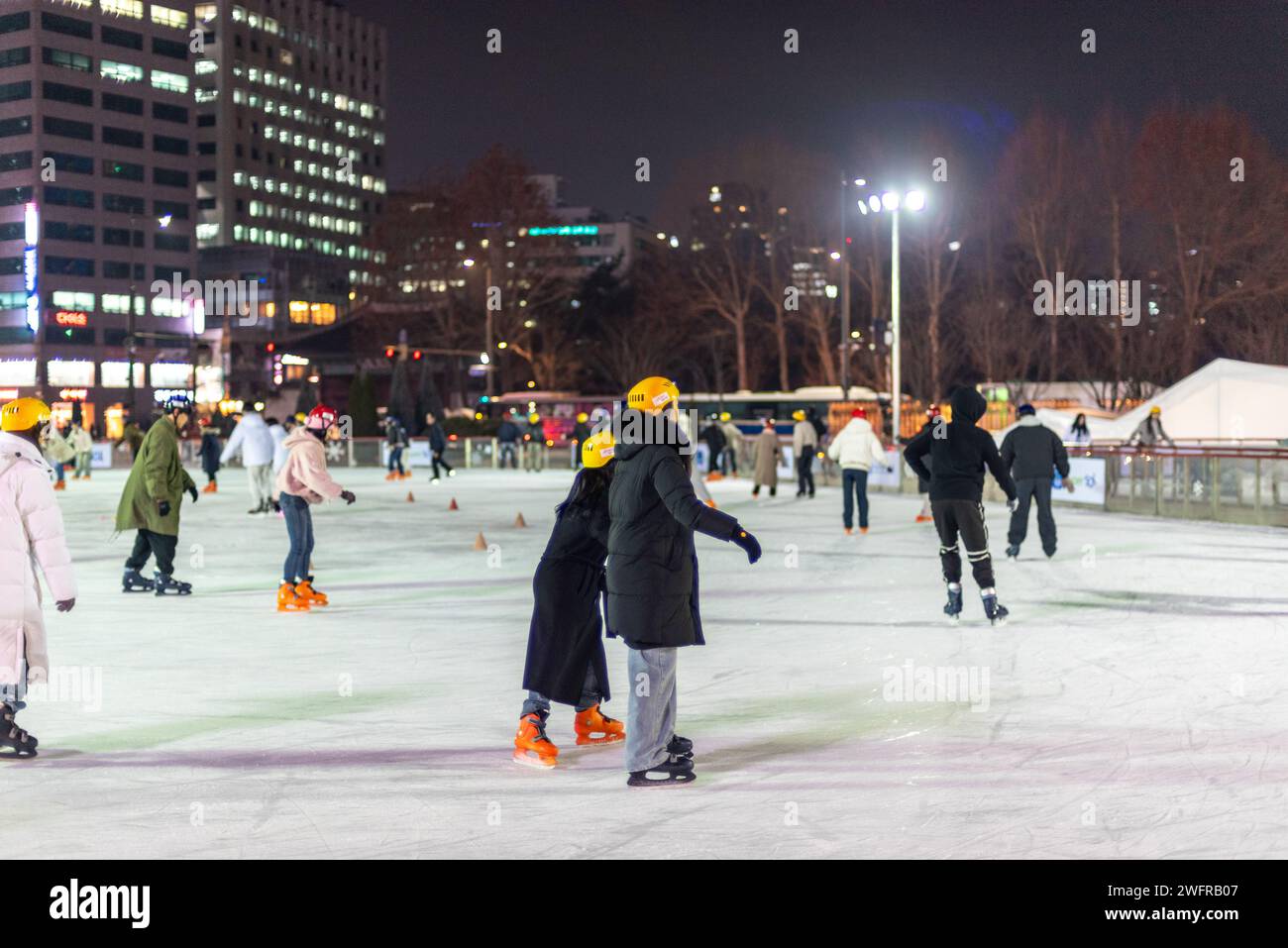 People ice skating at night on the temporary ice skating ring in front ...