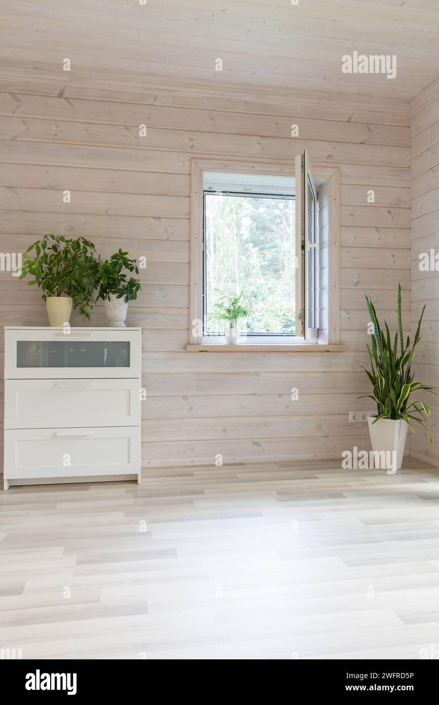 Open window in a room with indoor plants and a chest of drawers in a ...