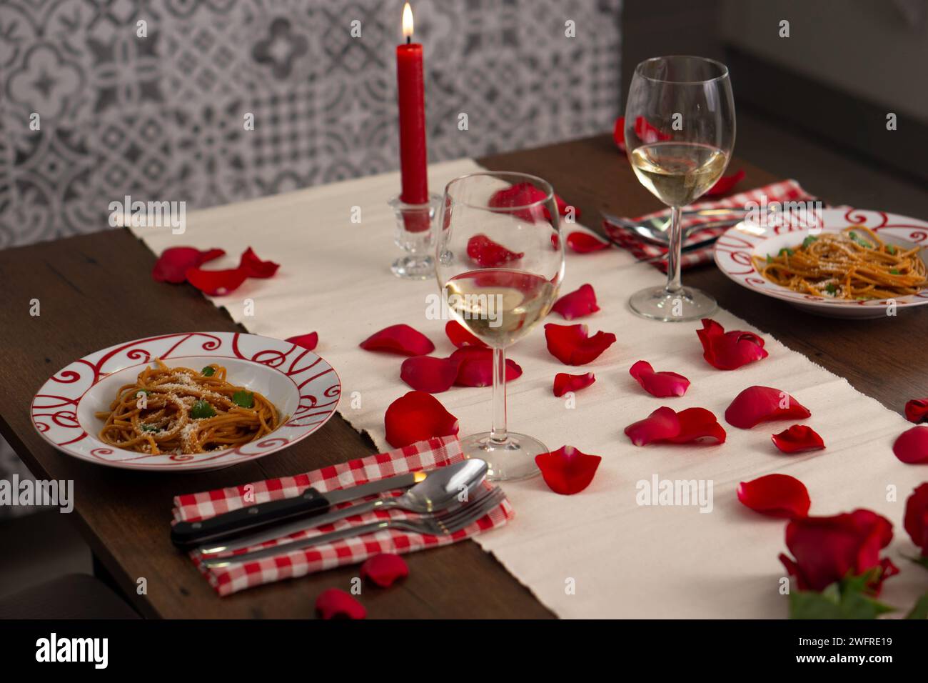 Dinner table set for two, with white wine, bolognese spaghetti and red ...