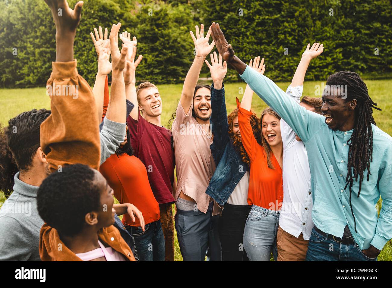 Exuberant diverse group of friends raising hands in celebration ...