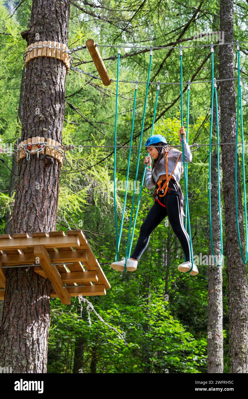 From below of teenage girl in sportswear walking on suspended rope ...