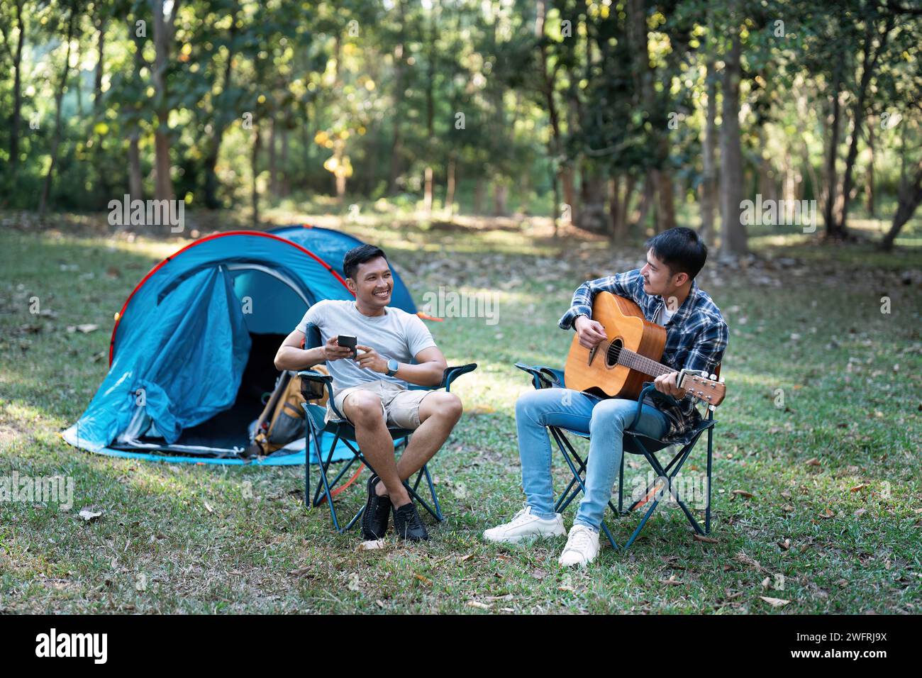 LGBTQIA Gay couple camping together in woods for holidays and relax on ...