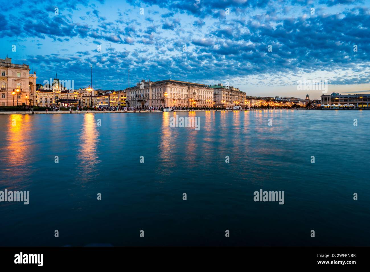 Dusk and night in Trieste. Between historic buildings and the sea Stock ...