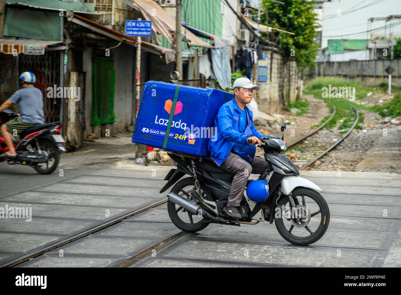 A Vietnamese Lazada delivery rider crossing a Level Crossing in Ho Chi ...