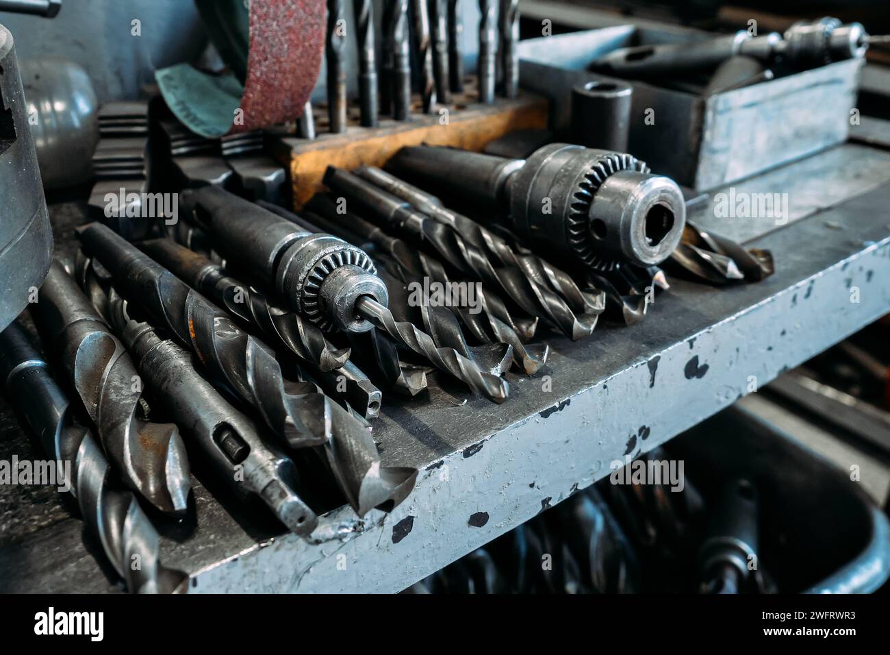 Set of metal drills lie on workbench in turning shop. Turning workshop ...