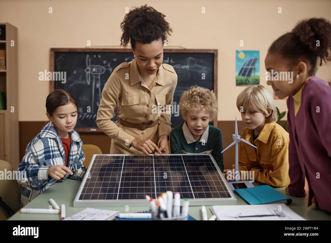 Diverse group of children learning about renewable energy in school ...