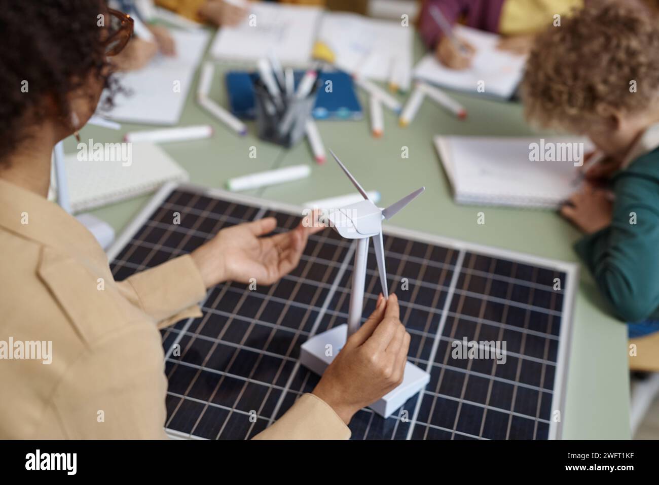 Close up of young teacher holding wind turbine model while explaining ...