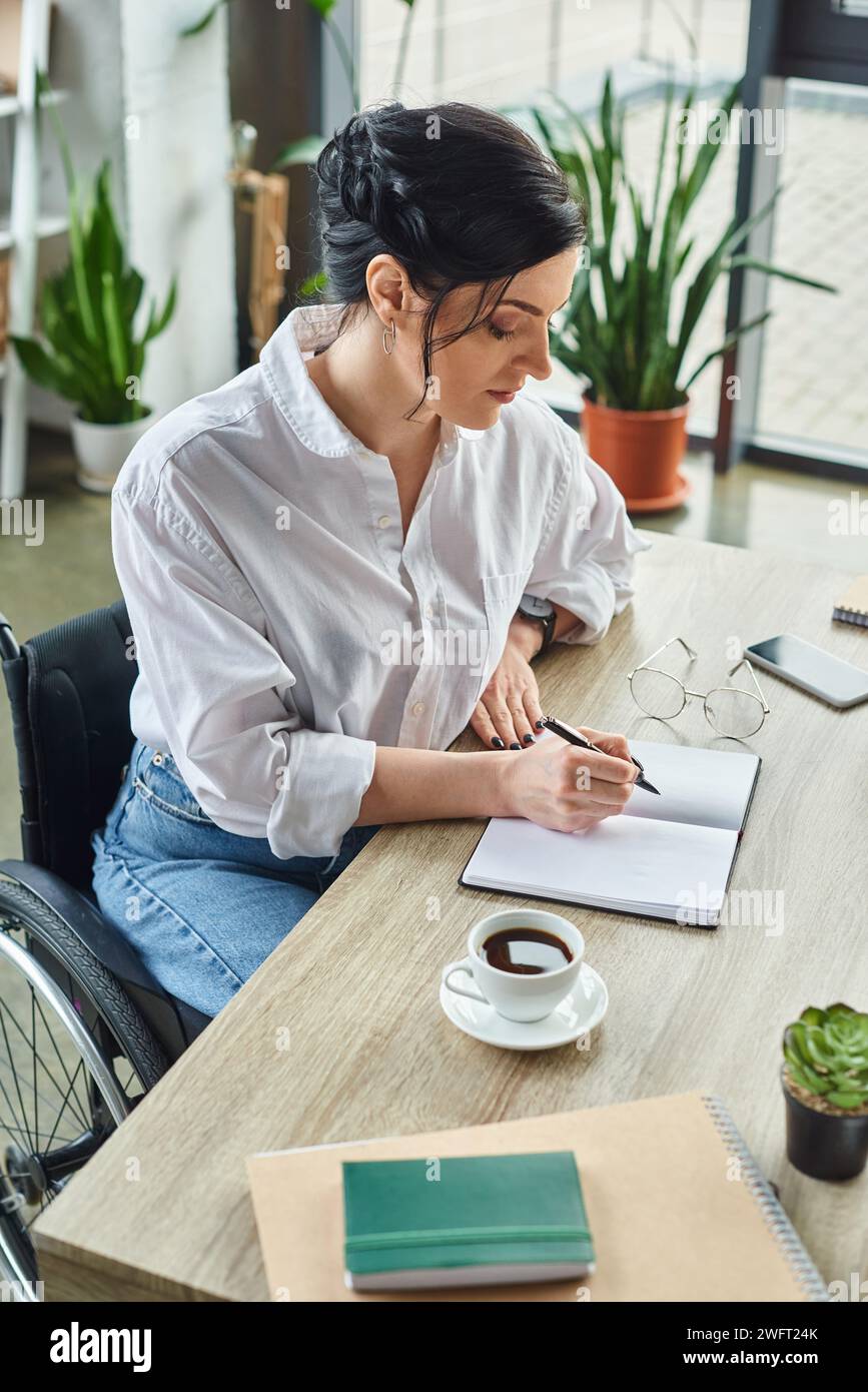 good looking disabled businesswoman in wheelchair taking notes while at ...