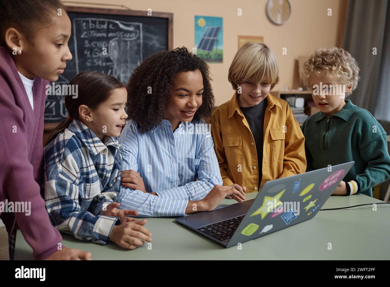 Portrait of smiling young Black woman as female teacher using computer ...