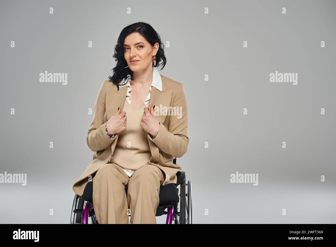 confident woman with disability in pastel elegant suit sitting in ...