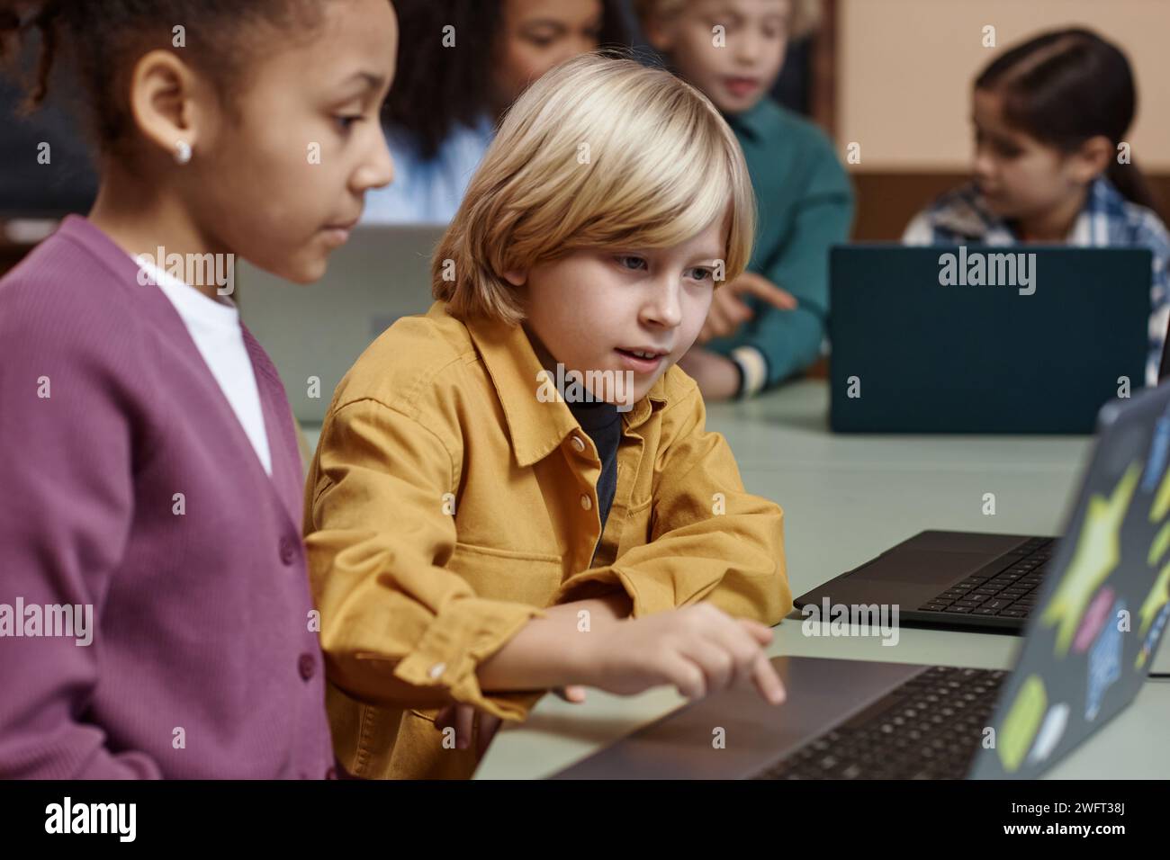 Side view portrait of blonde little boy using laptop and doing online ...