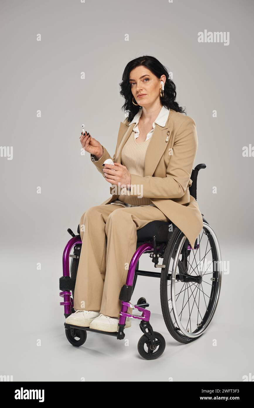 confident disabled woman in pastel suit in wheelchair putting on ...