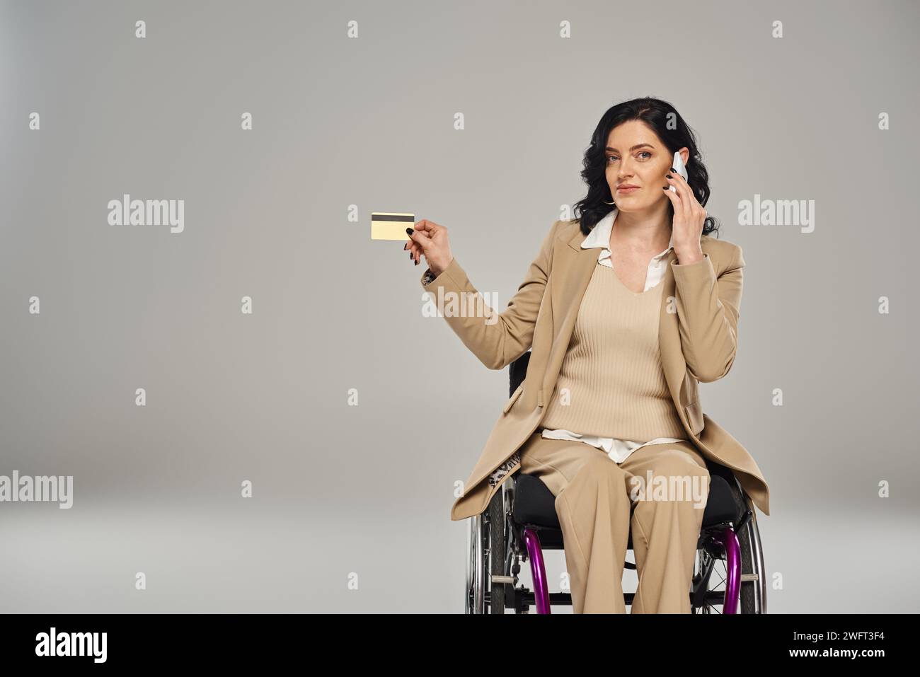 confident disabled woman in pastel suit in wheelchair holding credit ...