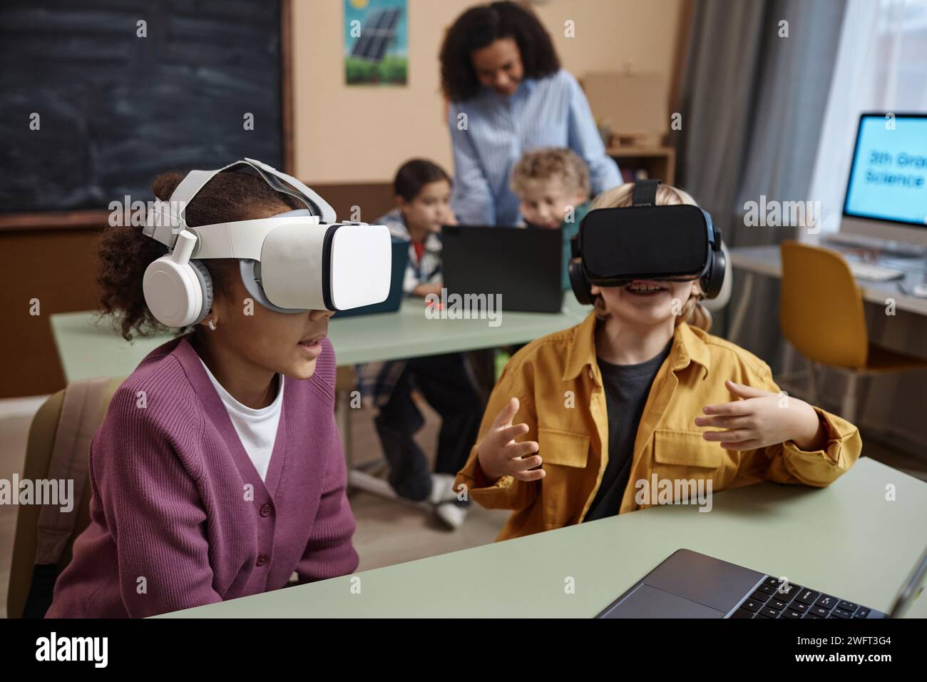 Portrait of two children wearing VR headsets in class and enjoying ...