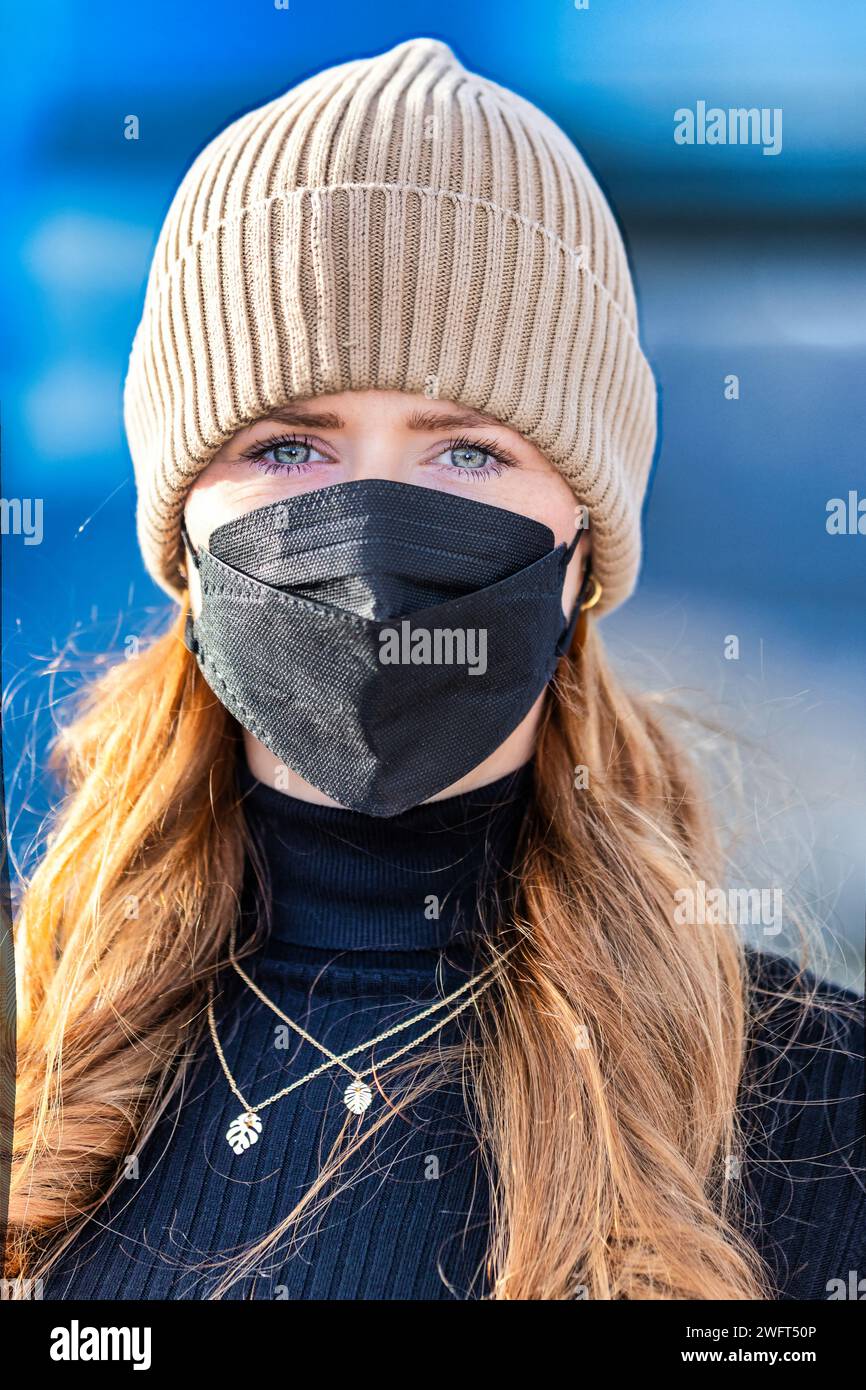 The picture shows a red -haired young woman, she wears an FFP 2 mask to ...