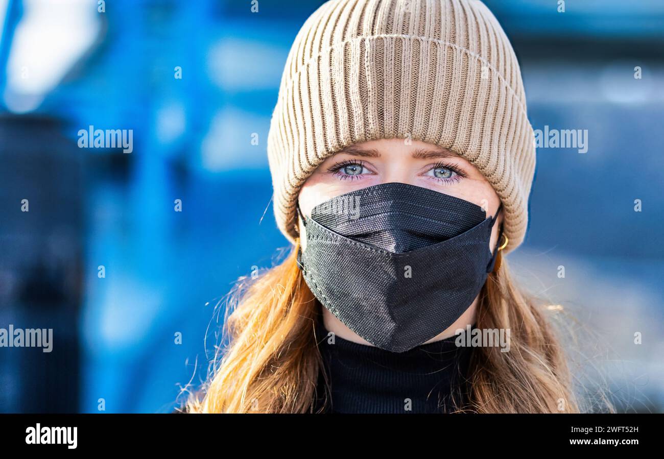 The picture shows a red -haired young woman, she wears an FFP 2 mask to ...