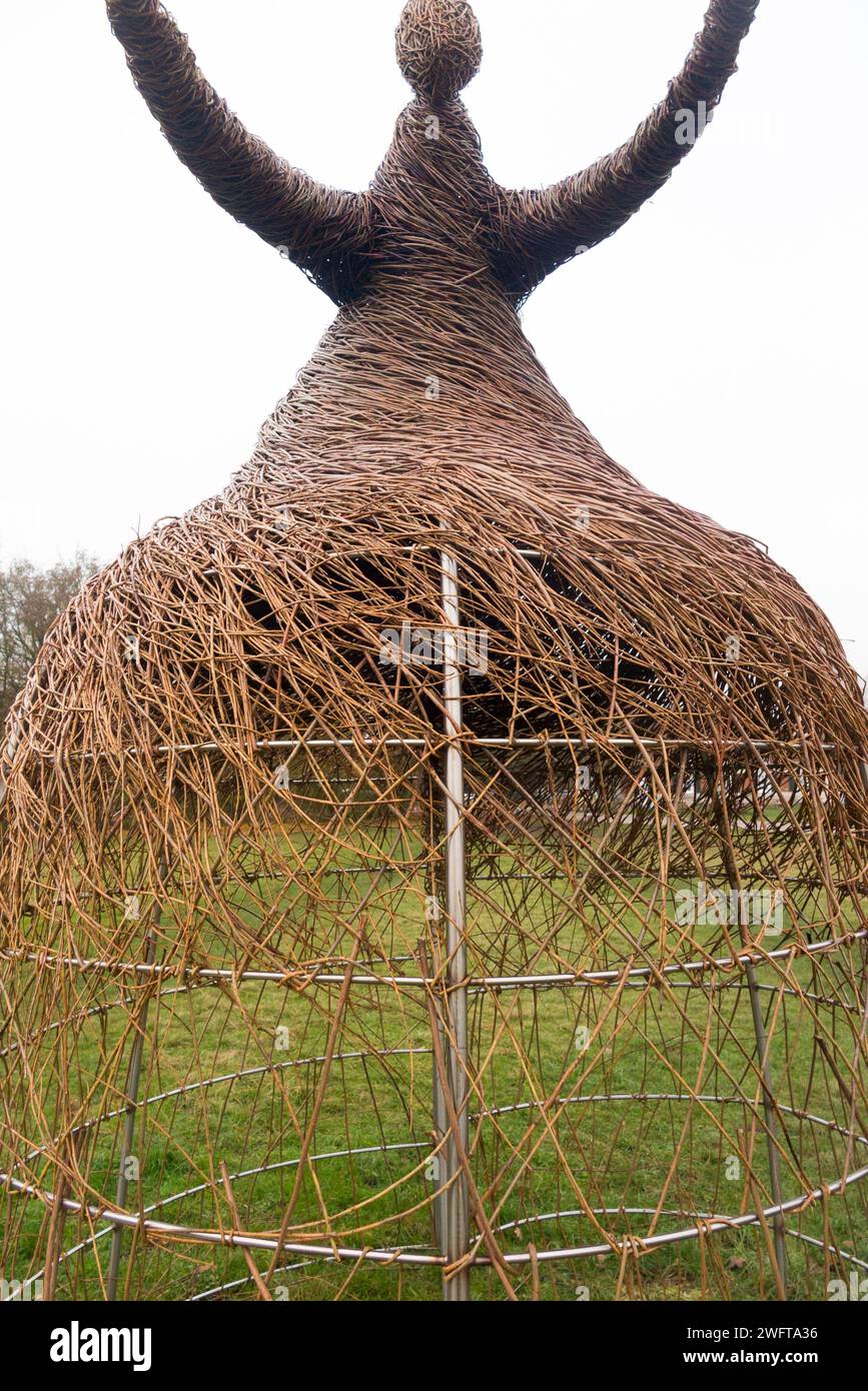 Sculpture of woman releasing bird (a peace dove perhaps), made from willow tree branches, by ...