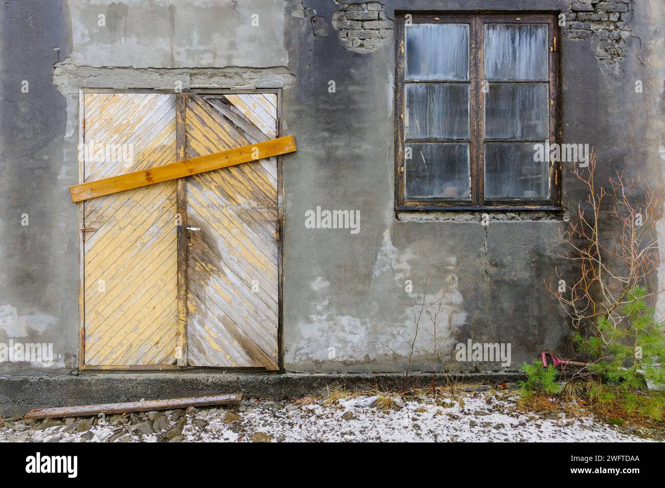A dilapidated structure with a heavily boarded door and a neglected ...