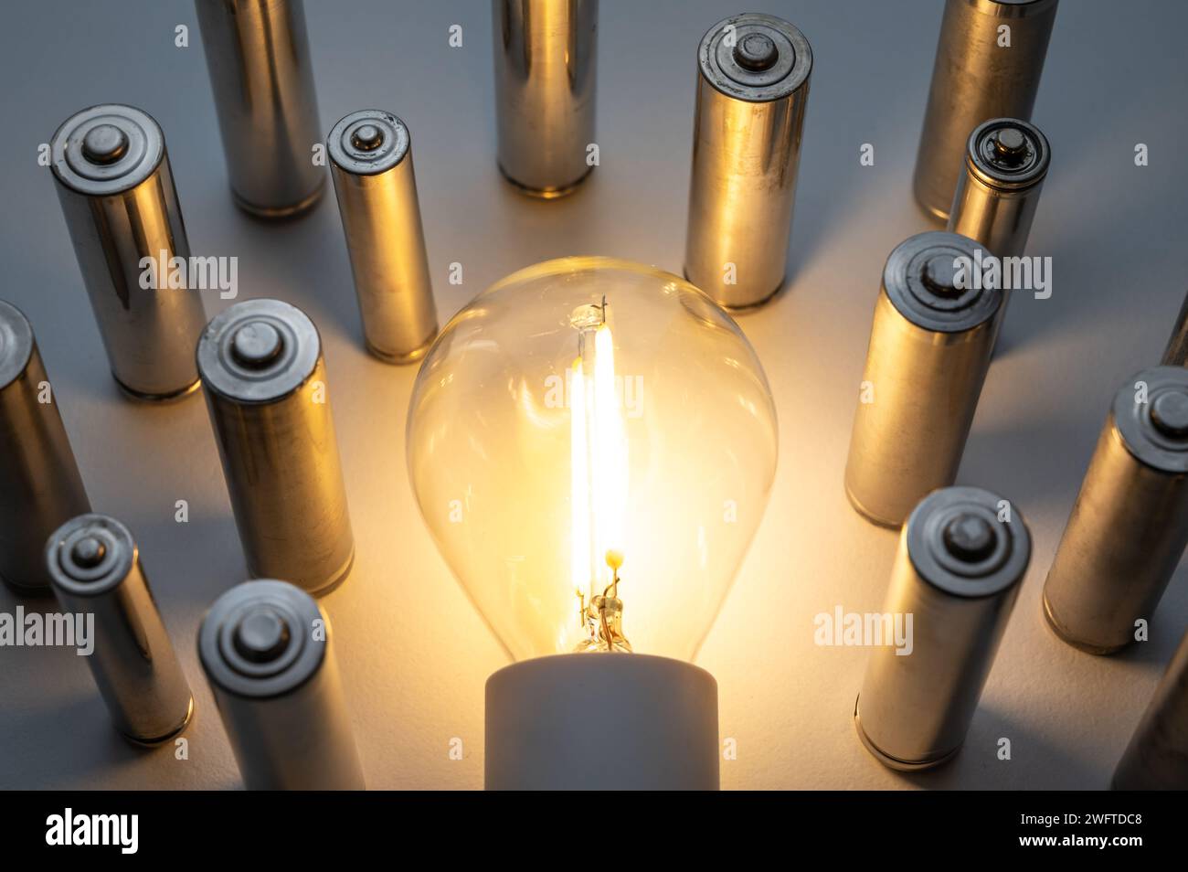 Light bulb turned on, with batteries next to it. Accumulation and reuse ...