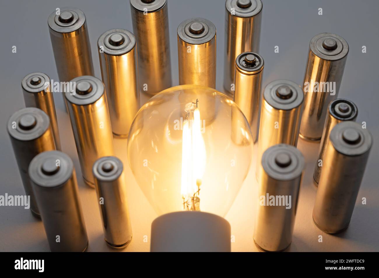 Light bulb turned on, with batteries next to it. Accumulation and reuse ...