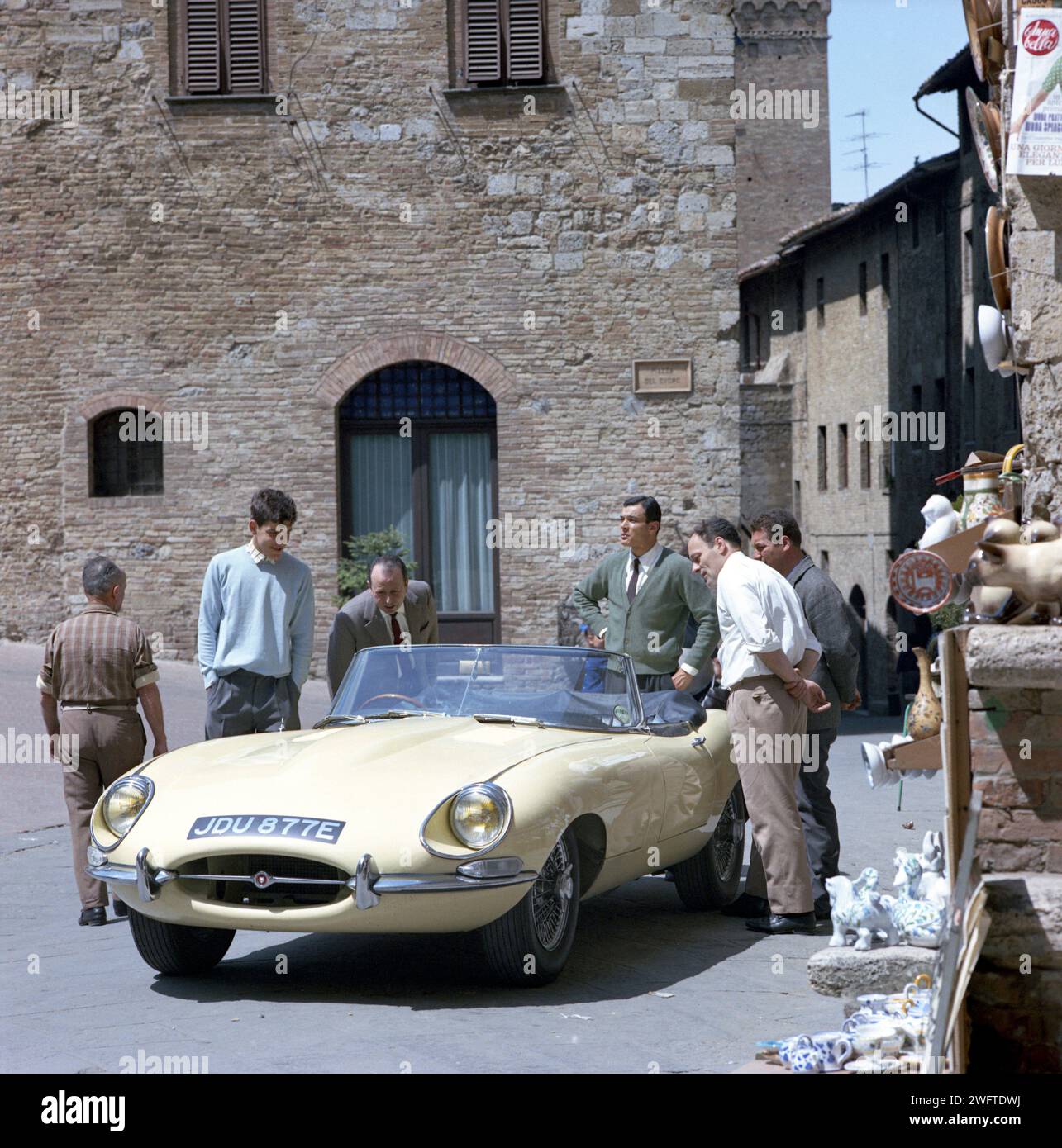 Onlookers admiring Primrose Yellow convertible Jaguar E-type parked ...