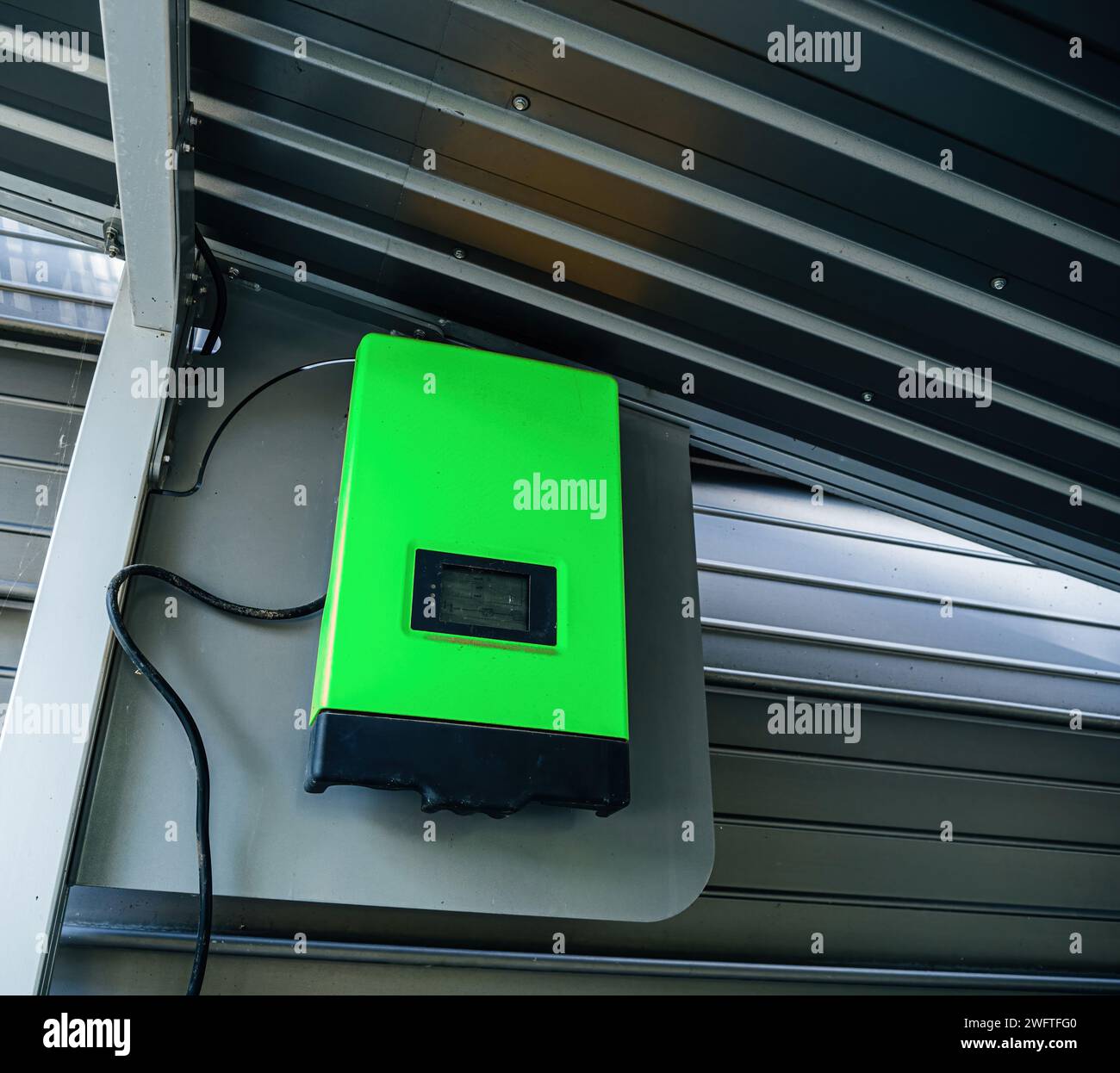 An industrial green solar power inverter installed on a metal garage ...