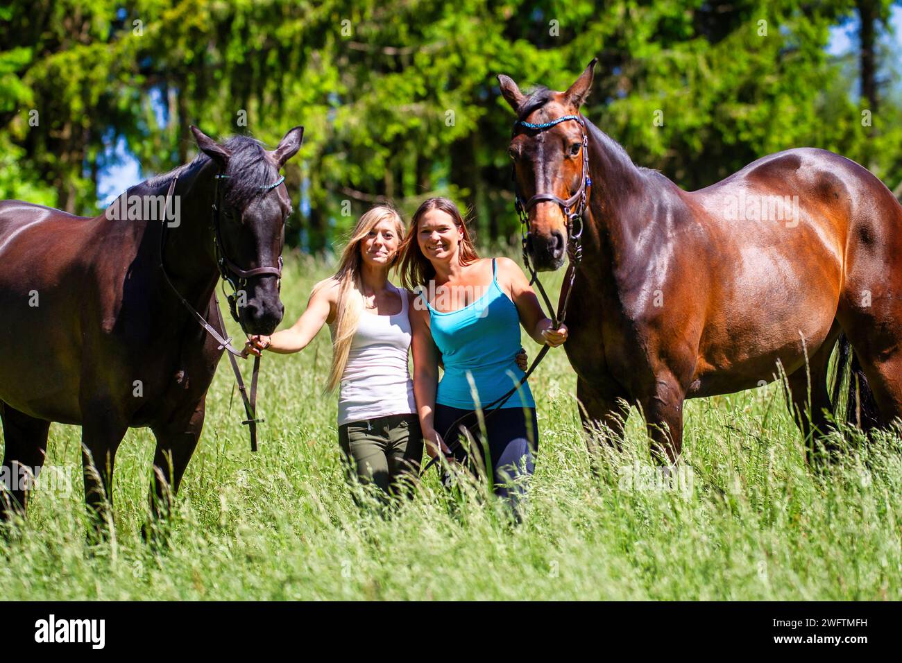 The picture shows two young women in light summer riding clothes with ...