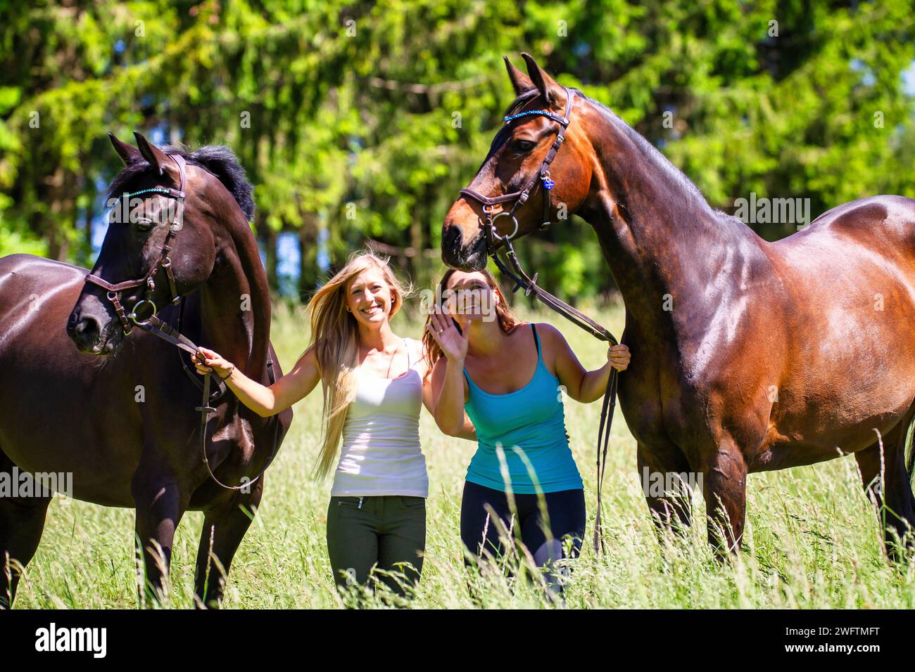 The picture shows two young women in light summer riding clothes with ...