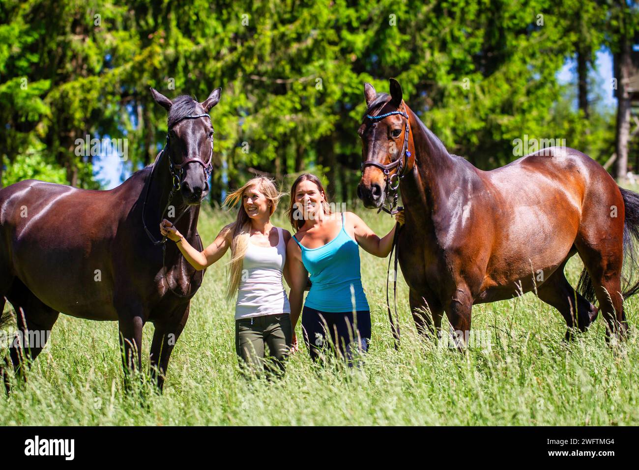 The picture shows two young women in light summer riding clothes with ...