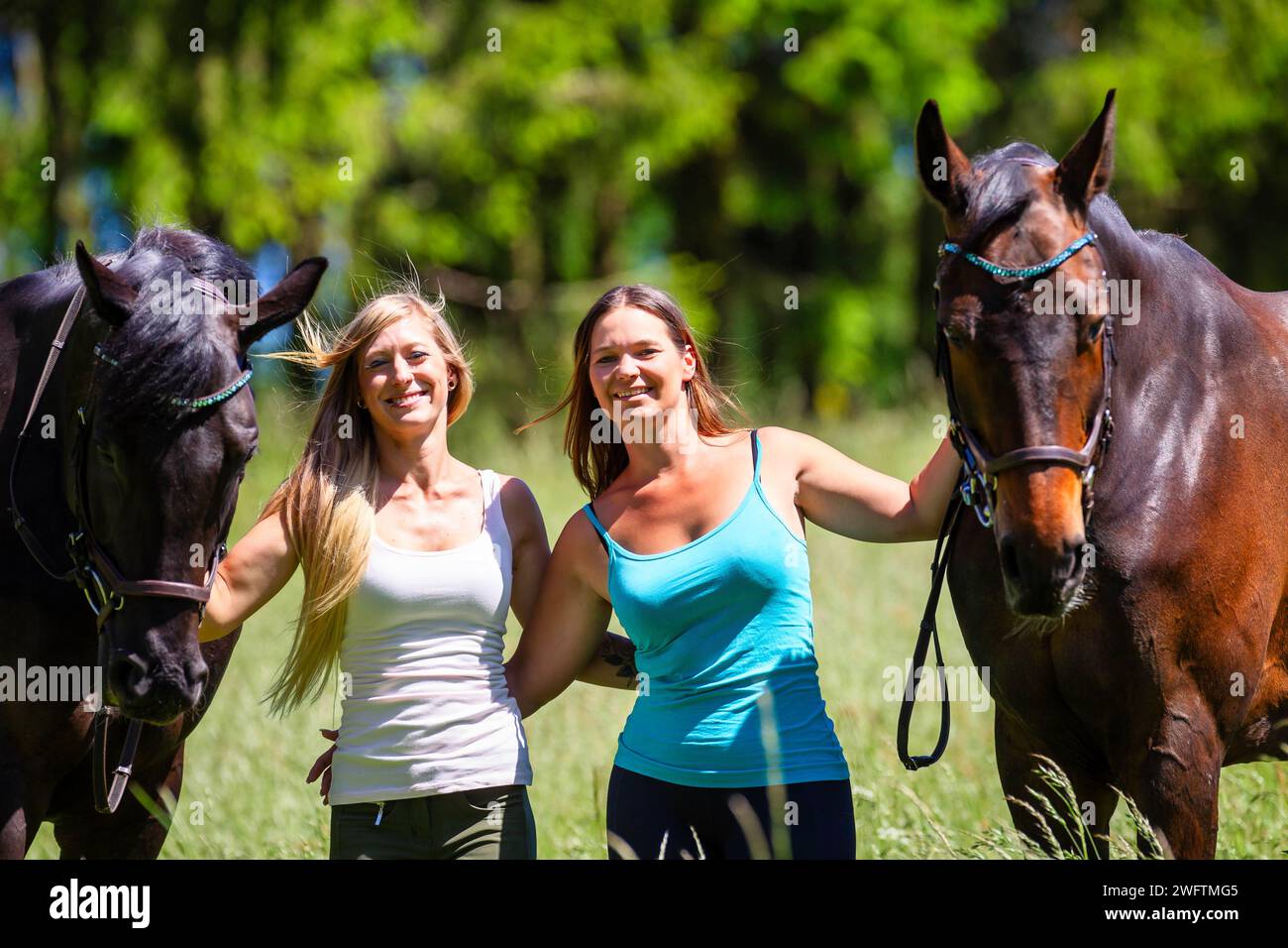 The picture shows two young women in light summer riding clothes with ...