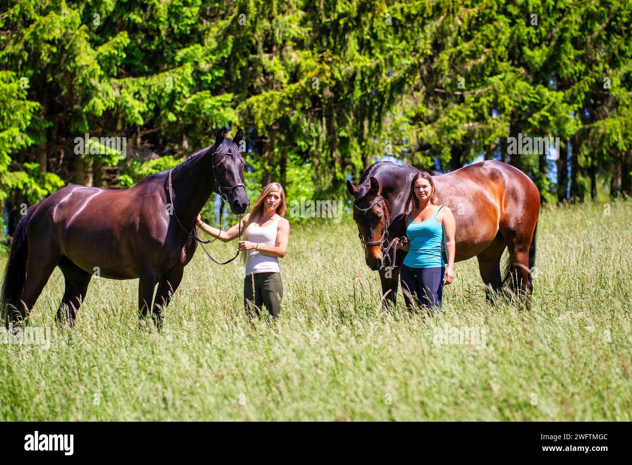 The picture shows two young women in light summer riding clothes with ...