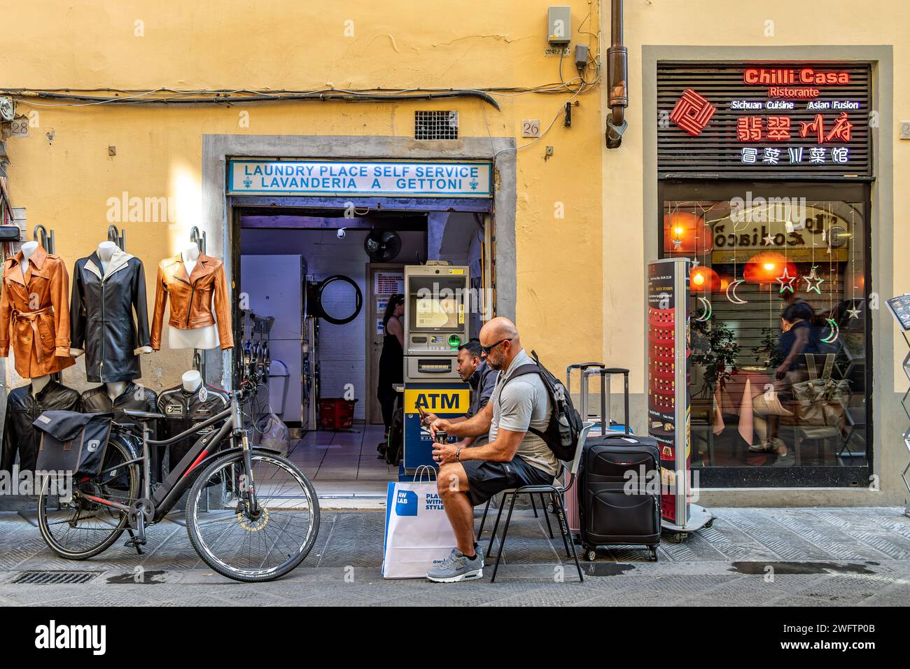 A woman using a launderette, lavanderia a gettoni, with two men sitting ...