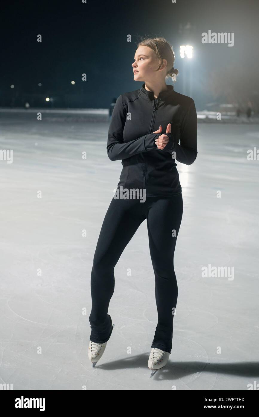 Beautiful young woman ice skating and performing short program over ...
