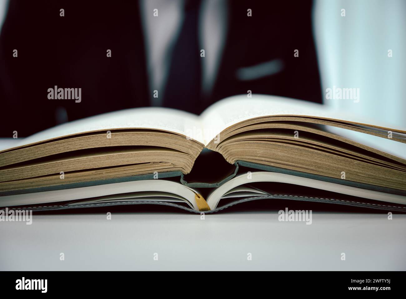 Thick book opened on desk in bookshop, a man in the background Stock ...