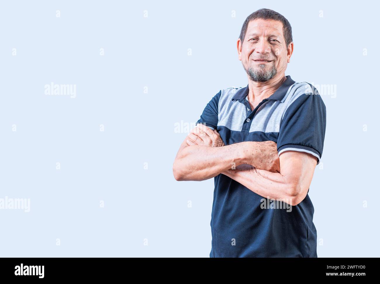 Smiling latin old man with arms crossed, casual on isolated background ...